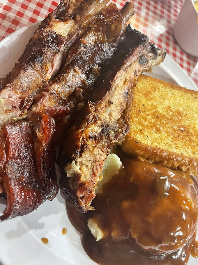 These smoke-kissed ribs aren't just falling off the bone—they're practically jumping onto your fork, accompanied by gravy-smothered mashed potatoes and Texas toast.