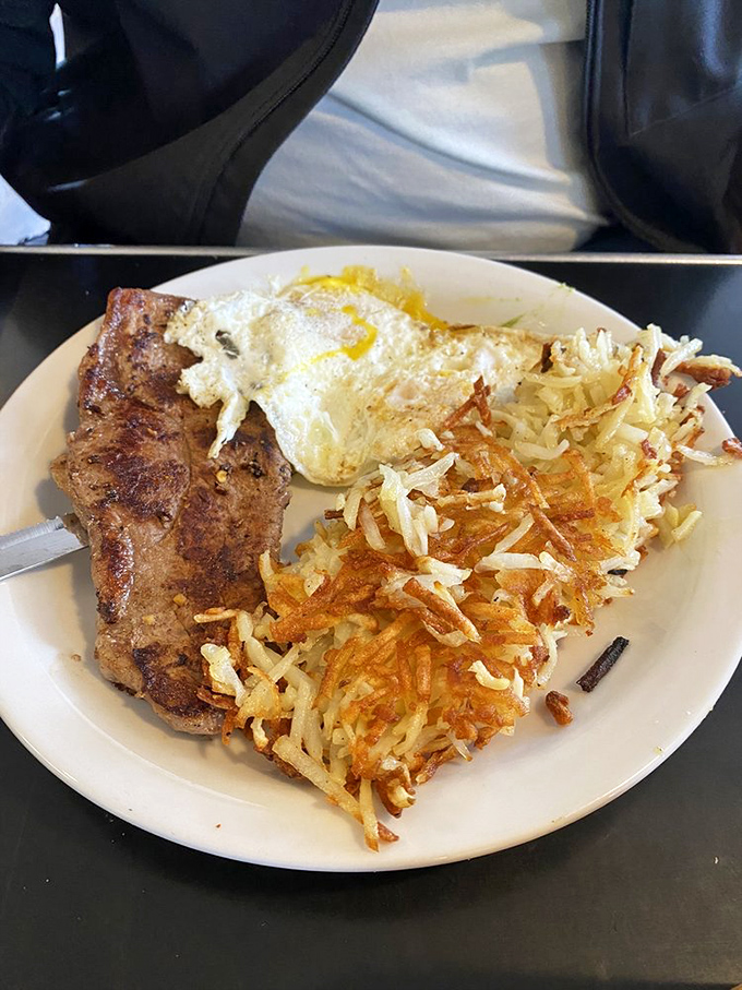 The breakfast of champions: a perfectly seared steak alongside sunny-side-up eggs and hash browns that achieve the golden crispy-to-fluffy ratio.