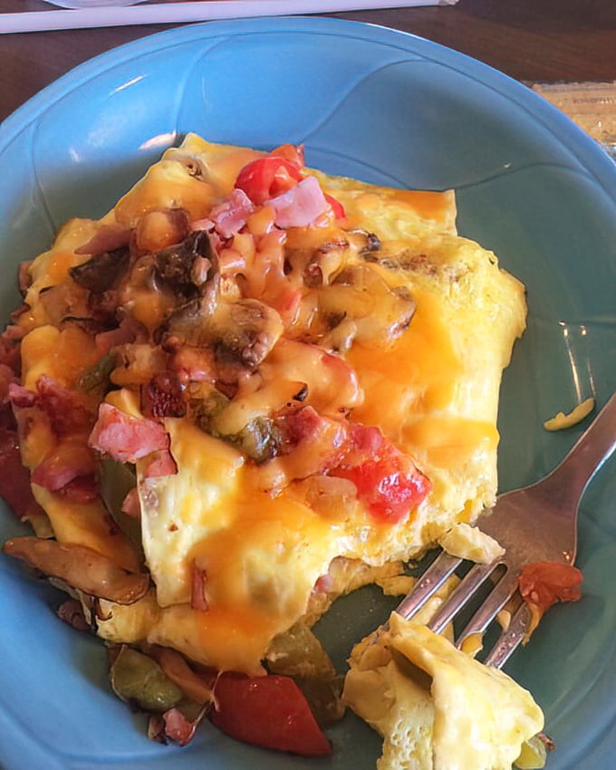 The supreme omelet arrives like a sunrise on a plate&mdash;cheese cascading over farm-fresh eggs studded with vegetables and ham.
