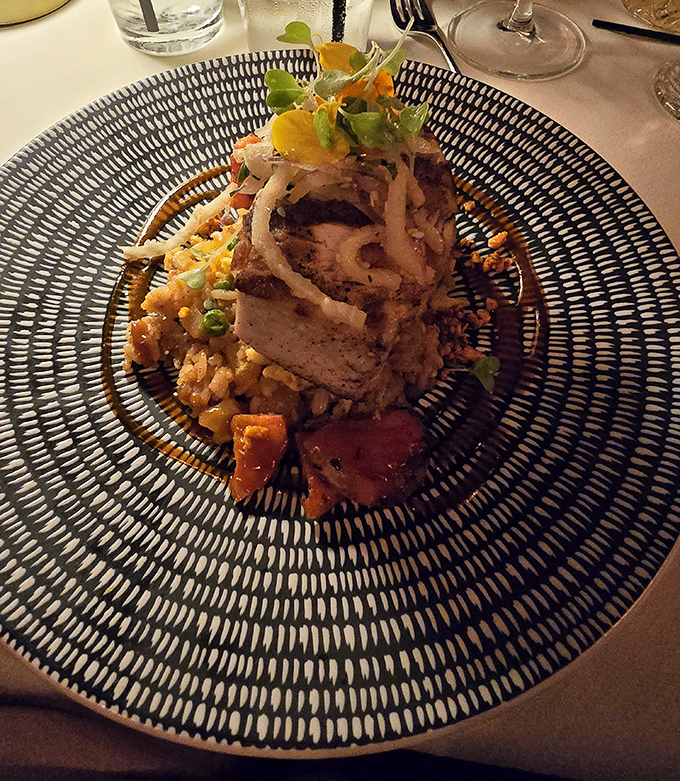 Architecture on a plate! This swordfish dish stands tall on a bed of colorful rice, crowned with crispy onions like a delicious skyscraper of flavor.