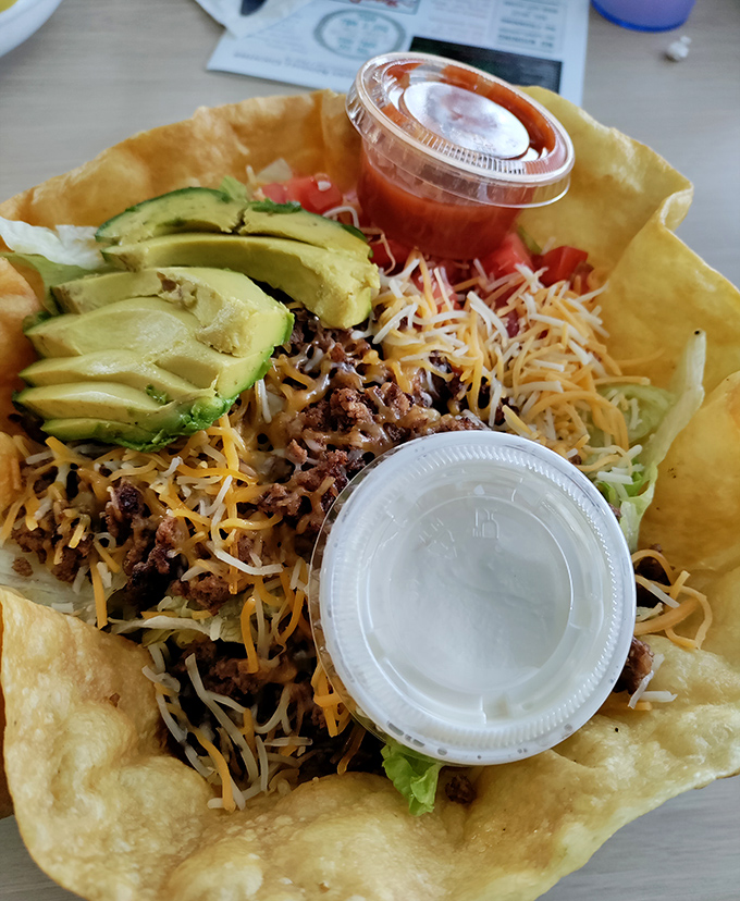 A taco salad that breaks free from its tortilla prison, spilling sunshine and flavor across the plate.