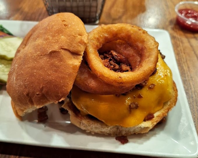 Melted cheese hugs the patty like it's never letting go, while a crispy onion ring stands guard atop this architectural marvel.