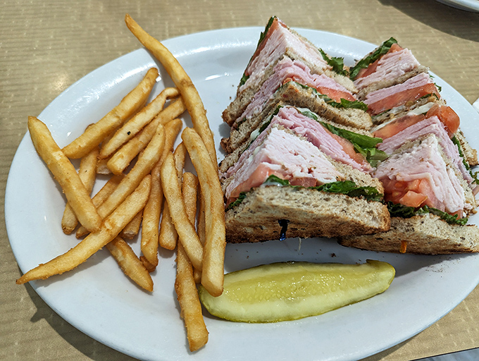The club sandwich: where turkey, bacon, and bread form a delicious skyscraper that requires both hands and a strategic eating plan.