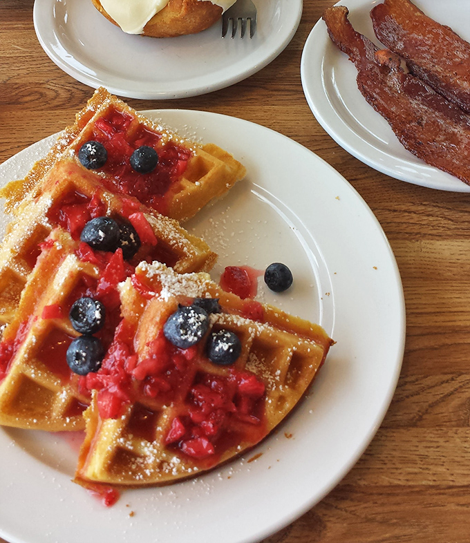 These waffles aren't just topped with berries &ndash; they're wearing them like jewelry. That bacon on the side is just showing off.