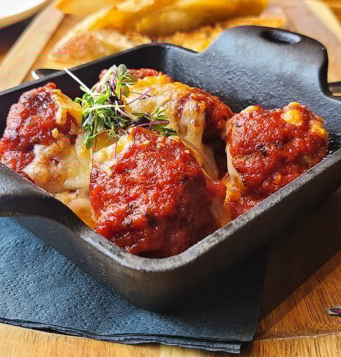 Wagyu meatballs nestled in their cast iron cocoon, swimming in tomato sauce that's been simmering since you made your reservation.