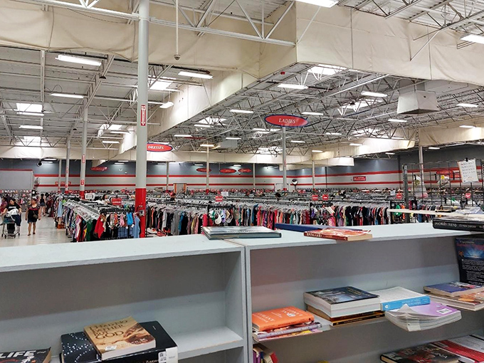 The book section whispers possibilities while clothing racks stretch to the horizon. In this cathedral of secondhand, salvation comes in finding the perfect fit.