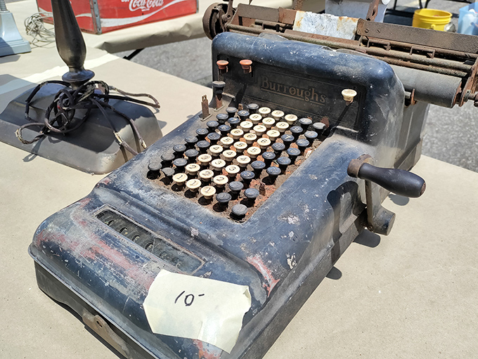 A vintage Burroughs adding machine sits silently, its mechanical keys a reminder of pre-digital commerce. Someone's great-grandfather probably cursed this very machine.
