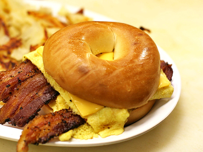 Breakfast architecture at its finest – a golden bagel sandwich stacked with eggs, cheese and bacon that makes morning meetings entirely optional.