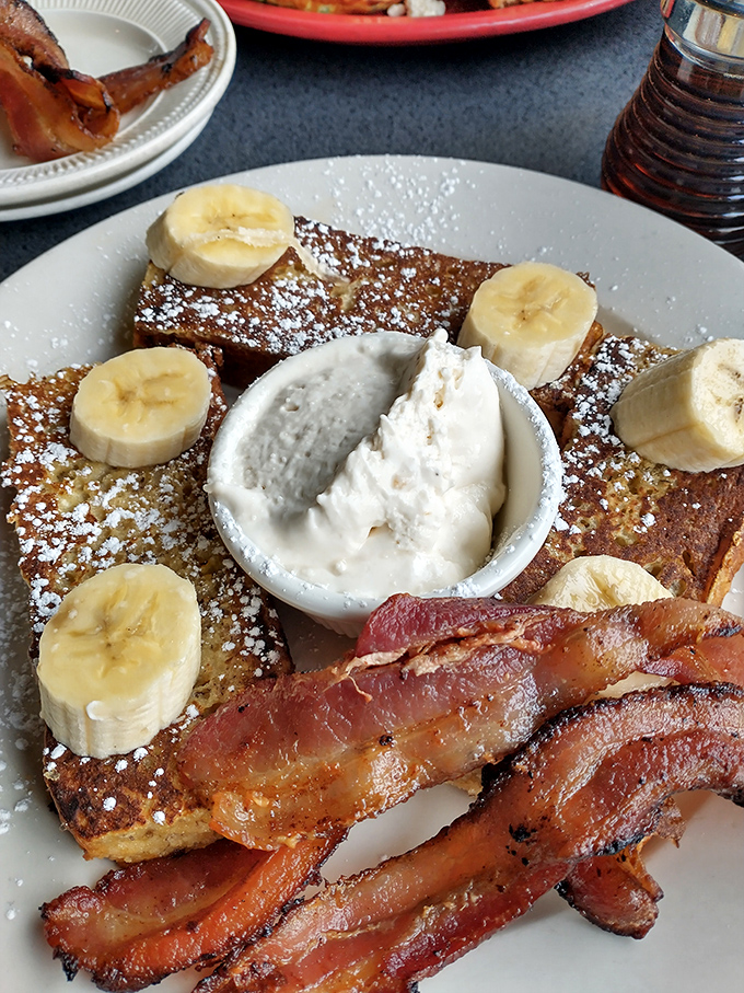French toast that makes you question all other breakfasts &ndash; challah bread transformed into a banana-topped masterpiece with bacon standing guard.