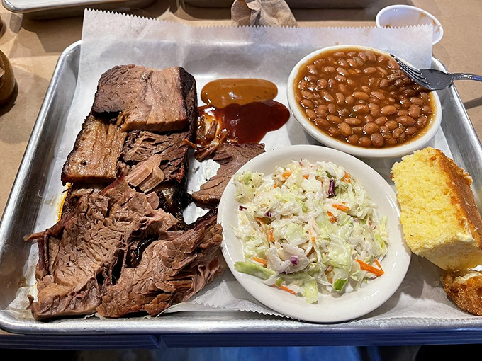 A barbecue trifecta: tender brisket, creamy cole slaw, and beans that have clearly been simmering with purpose. The cornbread is just showing off at this point.