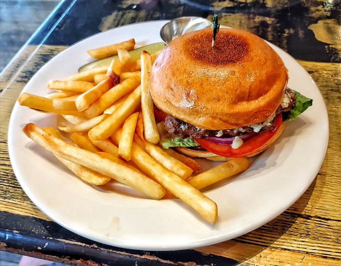 The burger arrives like a proper gentleman&mdash;well-dressed, substantial, and surrounded by golden fries that could make a French chef weep with joy.