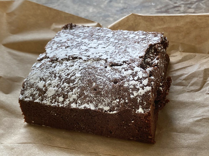 A chocolate brownie so dense and fudgy it could have its own gravitational pull, dusted with powdered sugar like fresh snow.