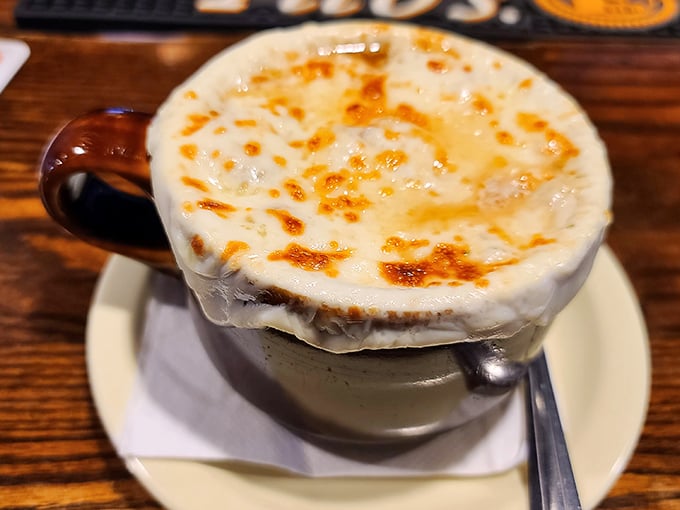Behold the French onion soup in all its glory—a volcanic cheese cap concealing a savory broth that's been simmering since before your last birthday.