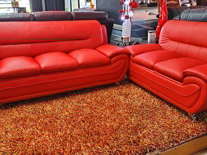 Those red leather sofas aren't just furniture; they're conversation pieces waiting to hear about your day while cradling you in budget-friendly luxury.