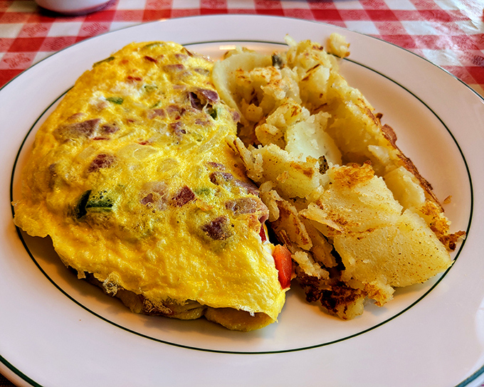 This isn't just an omelet; it's a golden envelope delivering a message of breakfast perfection alongside home fries that mean business.