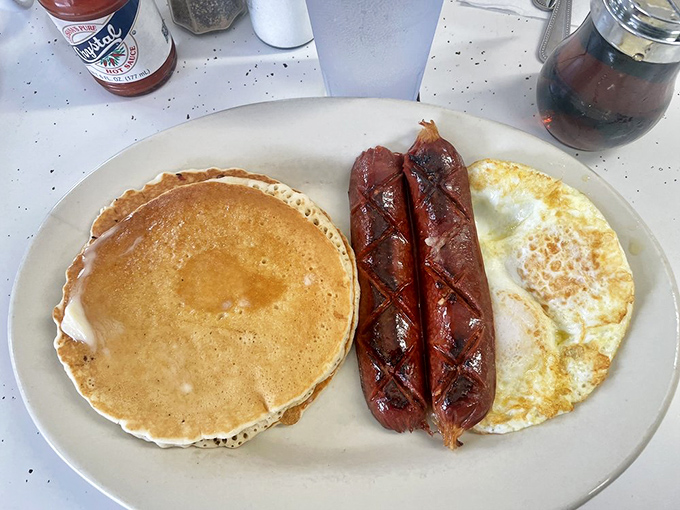 The breakfast holy trinity &ndash; golden pancake, perfectly cooked eggs, and those legendary smoked sausages glistening with just the right amount of char.