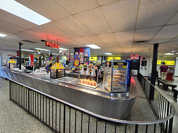 Stainless steel counters gleaming under "PIZZA" in neon red. The concession stand: where movie night meets comfort food paradise.
