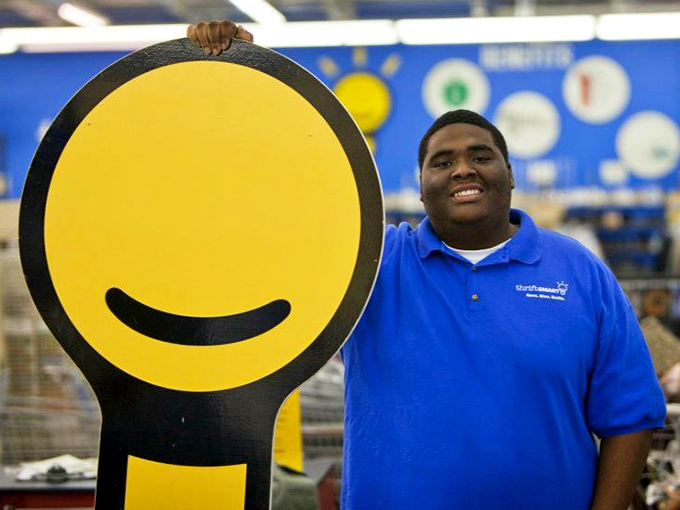 A friendly staff member showcases ThriftSmart's cheerful logo&mdash;proof that bargain hunting and community service can share the same smile.