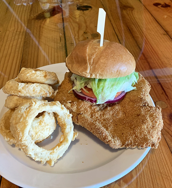This isn't just a sandwich, it's architectural achievement &ndash; crispy breaded tenderloin, fresh toppings, and those onion rings deserve their own zip code.