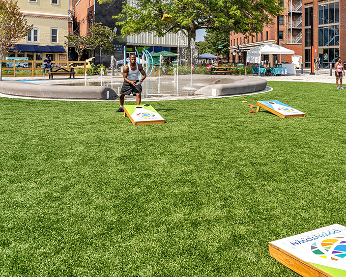 Nothing says "community" quite like a friendly game of cornhole in an urban green space where the grass is always greener than your lawn.