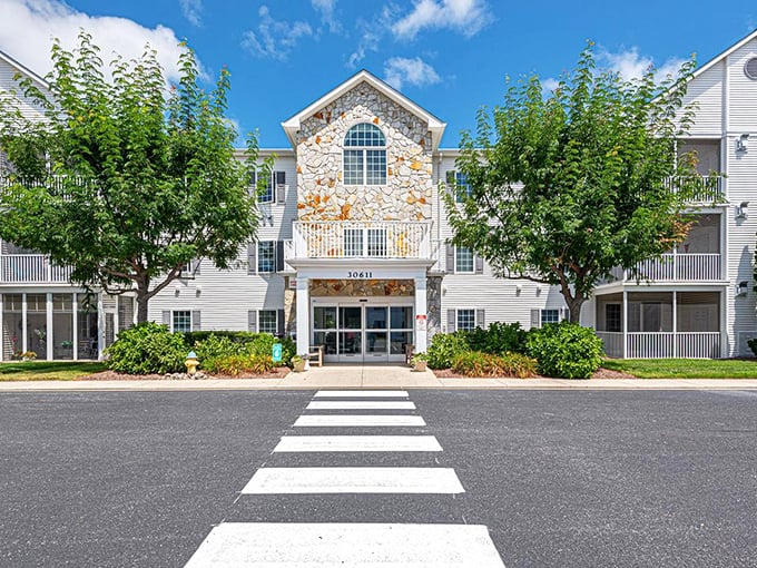 Cedar Bay's stone facade gleams in the sunshine, framed by leafy trees. Resort-style living without the resort-style prices!