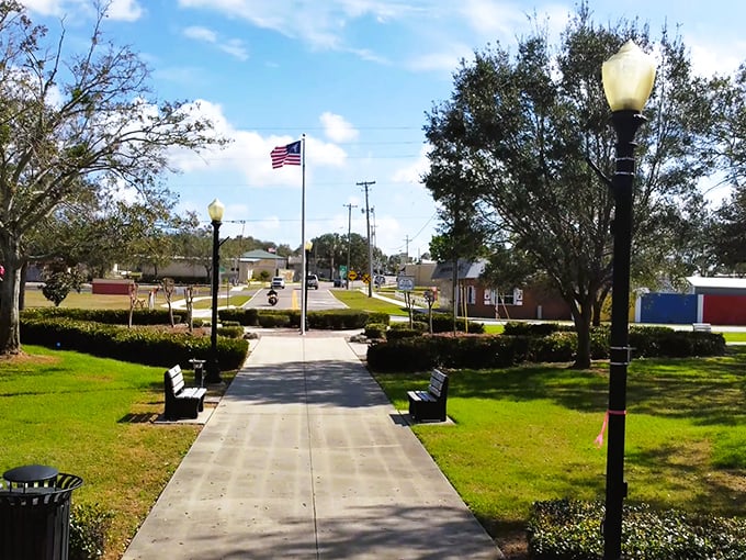 A charming view of Lake Placid&rsquo;s welcoming park, complete with benches, bright green lawns, and the American flag.