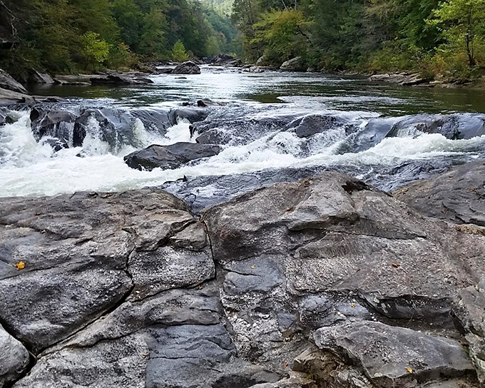 Nature's own symphony cascades over ancient rocks, where rushing waters create the perfect soundtrack for mountain contemplation.