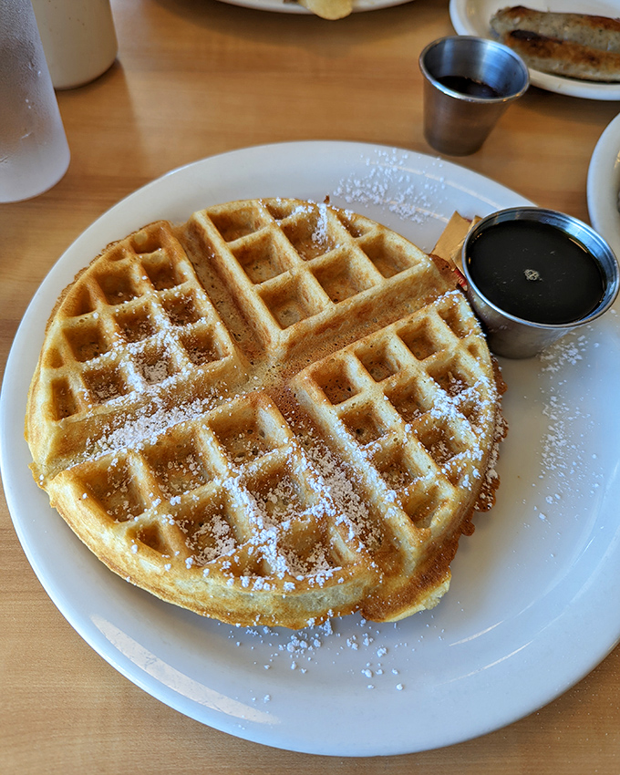 This Belgian waffle isn't just breakfast, it's architecture you can eat, complete with powdered sugar snow and maple syrup rivers.