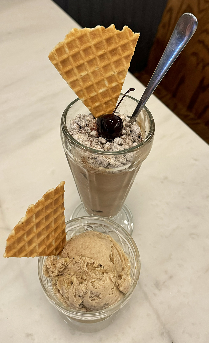 A perfect pairing: creamy ice cream in a glass with a waffle garnish meets its soulmate&mdash;a scoop in a dish that's patiently waiting its turn.
