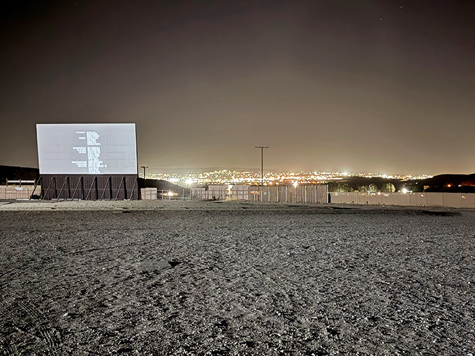 After dark, the illuminated screen glows like a beacon against the night sky, with city lights twinkling in the distance.