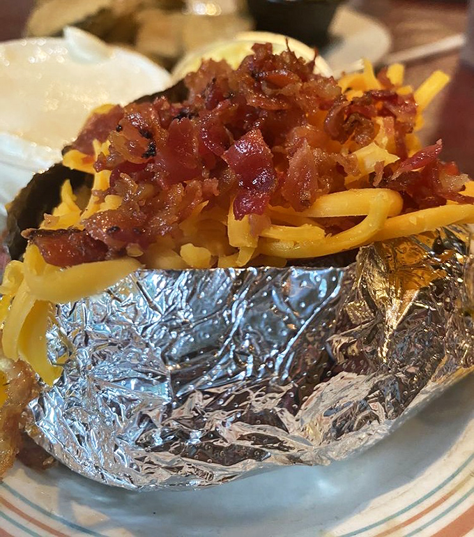 A loaded baked potato that's dressed for success with cheese, bacon, and all the fixings—carb heaven wrapped in aluminum foil.