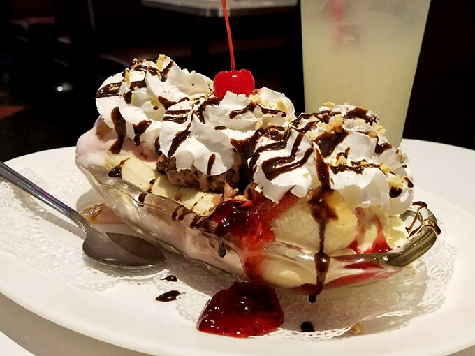 The banana split arrives like a dessert parade, layers of ice cream, whipped cream, and toppings performing a sweet symphony in a classic boat dish.