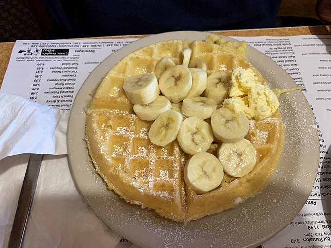 This Belgian waffle topped with bananas isn't just breakfast, it's an architectural achievement that somehow bridges the gap between virtue and indulgence.