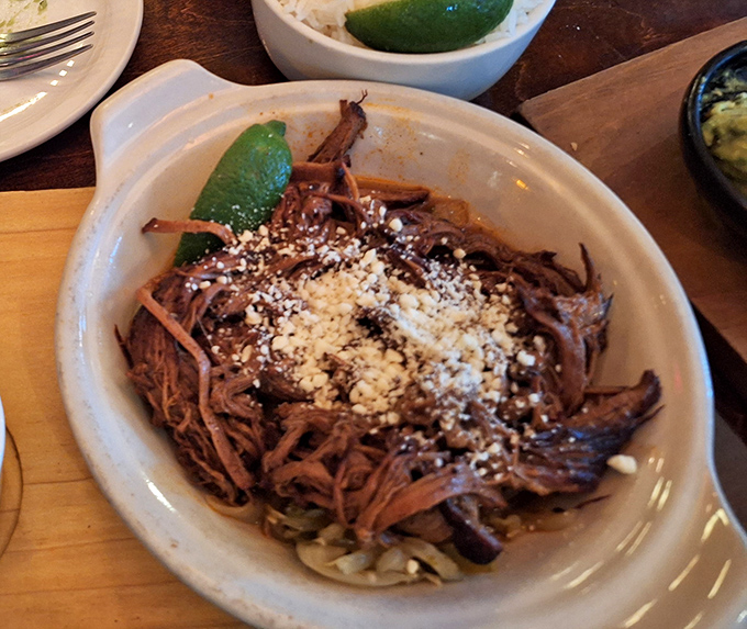Barbacoa so tender it practically surrenders to your fork, crowned with cotija and served with lime wedges for that perfect acid balance.