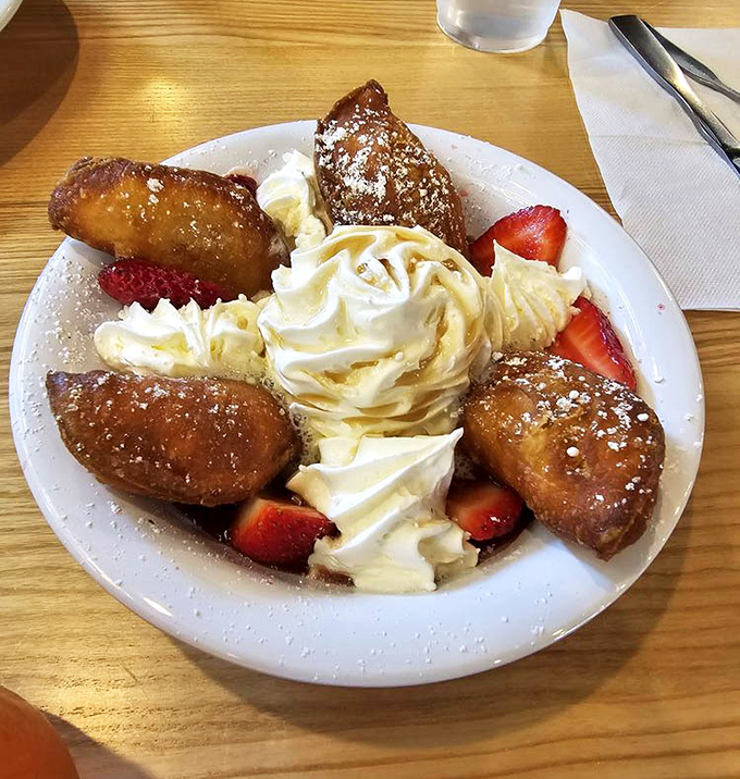 Golden beignets arrive like little pillows of joy, dusted with magic and filled with strawberry dreams.
