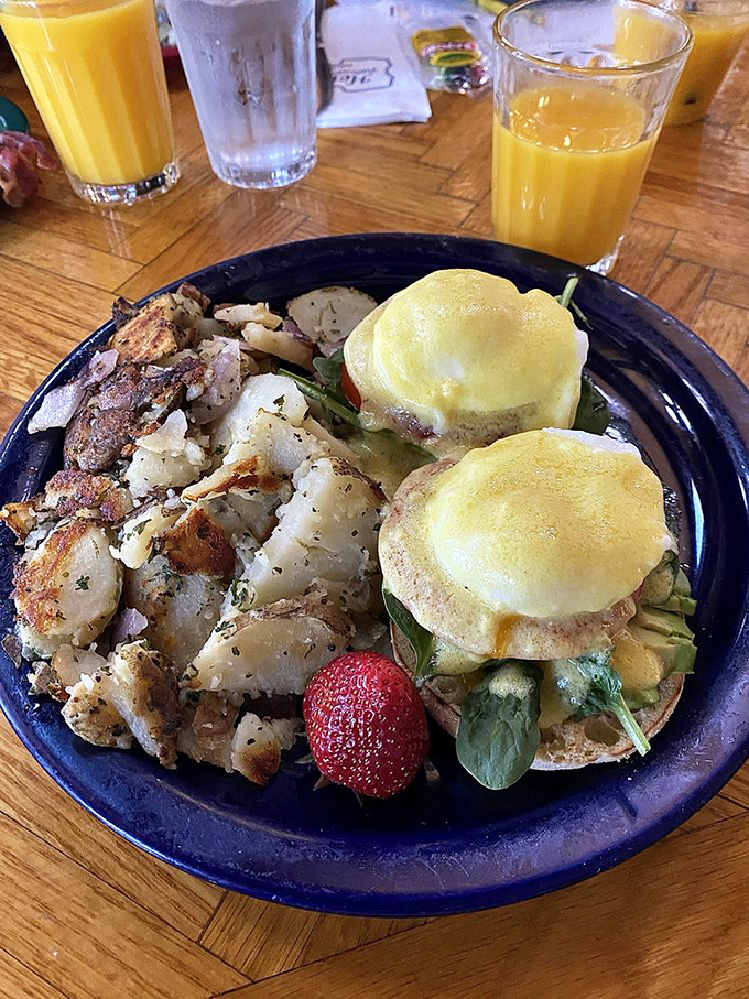 Benedict perfection: English muffins providing the stage where perfectly poached eggs perform their runny yolk magic alongside crispy potatoes.