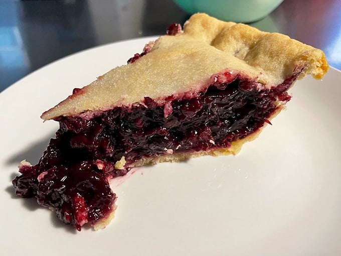 A slice of berry pie that belongs in the Louvre, not just on your plate. The crimson filling practically whispers sweet nothings to your fork.