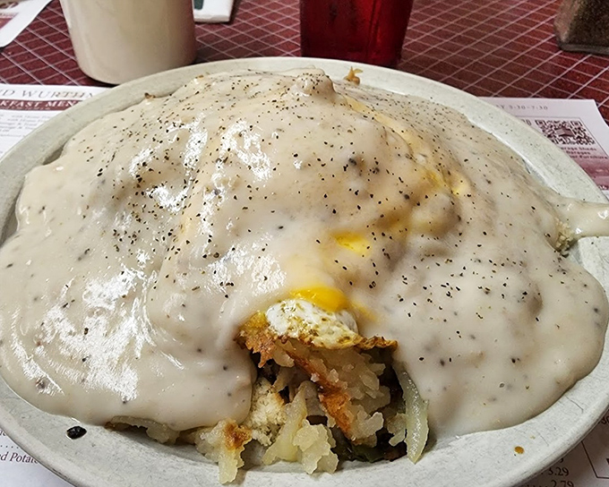 Breakfast nirvana: a mountain of creamy pepper-flecked gravy cascading over potatoes and biscuits, with just a peek of egg underneath.
