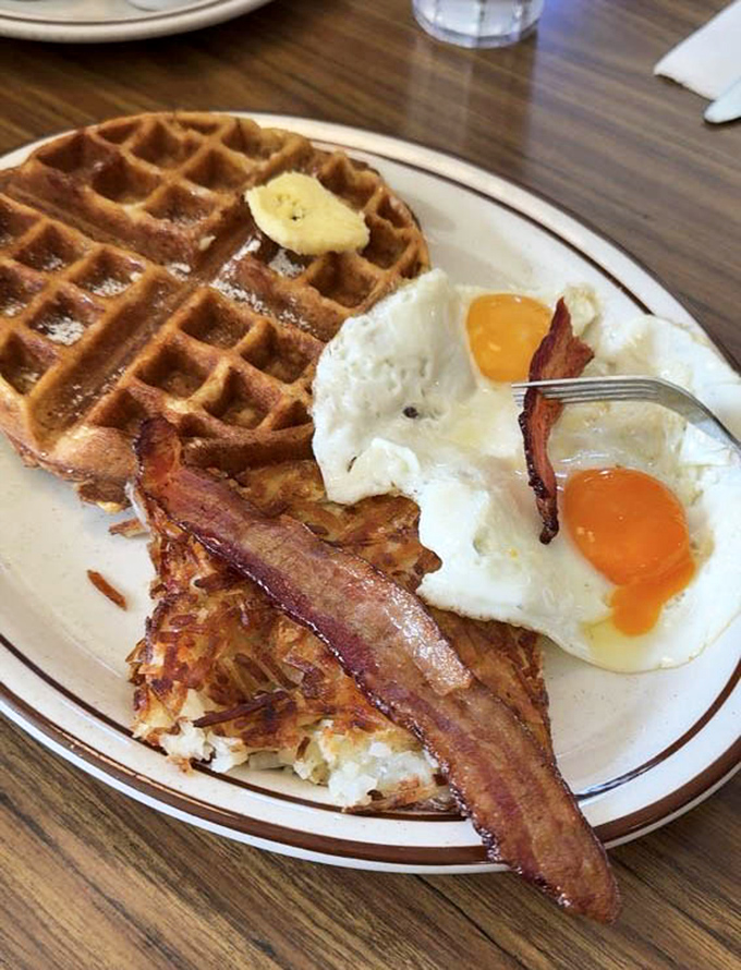 The breakfast trinity—golden waffle, sunny-side-up eggs, and bacon cooked to that perfect crisp-yet-chewy state that's harder to achieve than work-life balance.