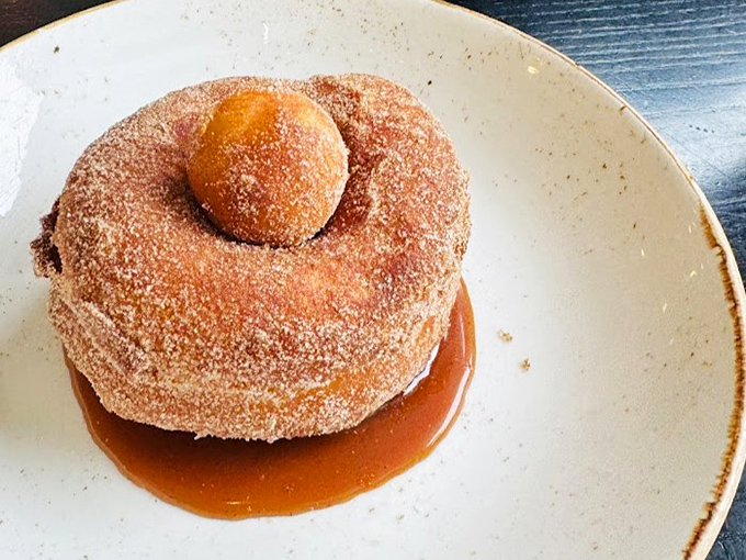 Sugar-dusted brioche doughnut lounging in a pool of caramel. Resistance is futile, diets are postponed.