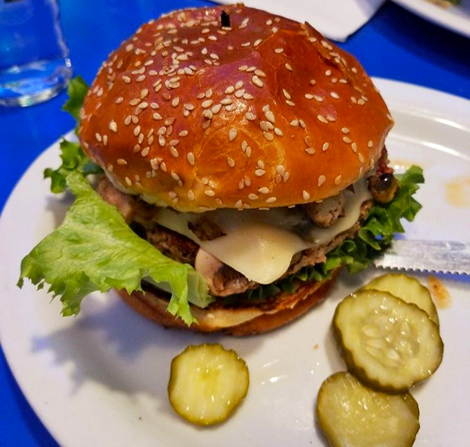 A burger that requires both hands and your full attention. The sesame-studded bun barely contains the deliciousness trying to escape.