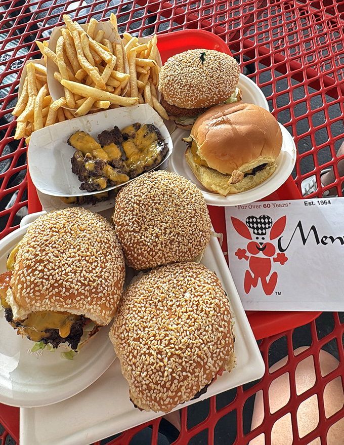 A red picnic table feast that would make any food photographer swoon. These aren't just burgers&mdash;they're edible American icons with cheese.