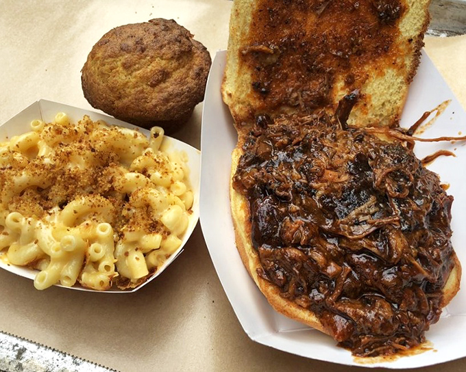 Comfort food trifecta: creamy mac and cheese, a perfect cornbread muffin, and pulled pork sandwich that makes you question why you'd eat anything else.