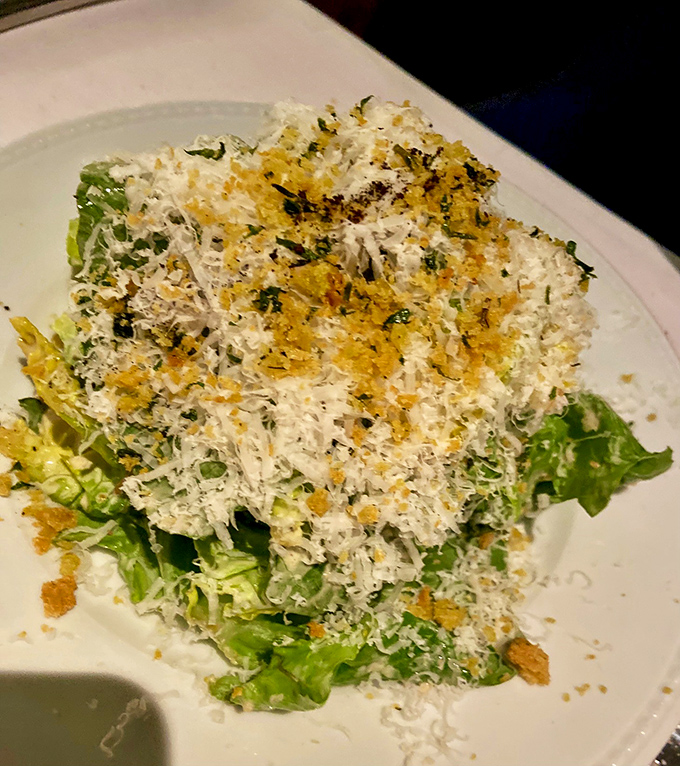 The Caesar salad arrives under a snowfall of cheese and croutons, proving that sometimes the classics remain undefeated for good reason.