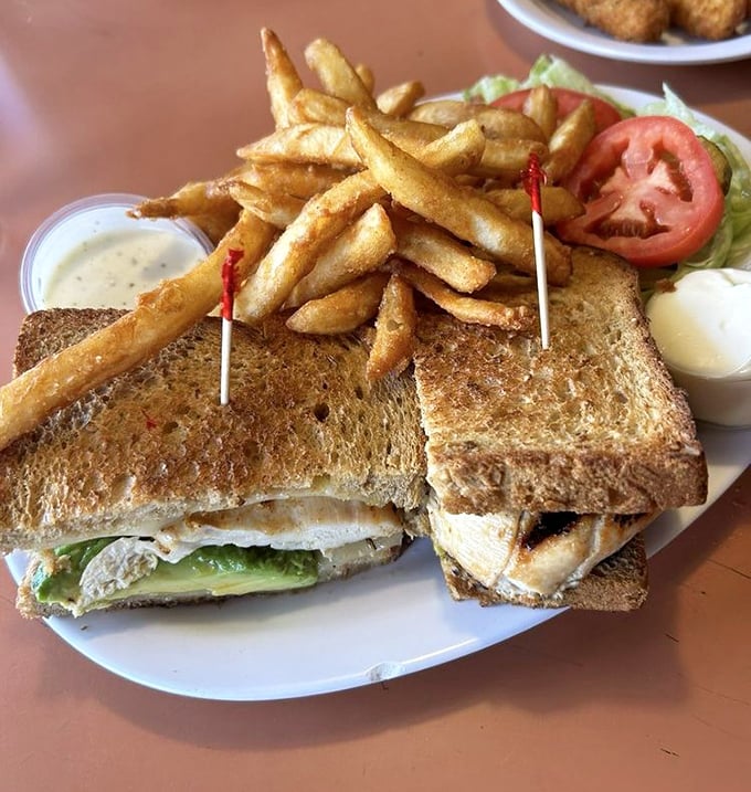 A sandwich that requires engineering skills to eat—layers of avocado, chicken and veggies between toast that somehow defies structural collapse.