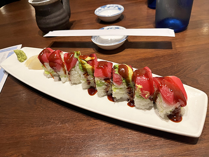 Sushi that looks like edible art - vibrant tuna slices draped over rice like tiny red blankets, with avocado adding creamy contrast.