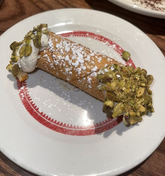 Not just dessert, but a grand finale: a cannoli with pistachios standing guard over sweet ricotta like it's Fort Knox for flavor.