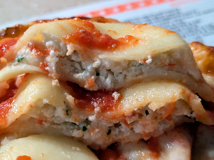 The cheese ravioli cross-section reveals the truth&mdash;pillowy pasta pockets filled with herb-flecked ricotta, all swimming in that signature sauce that haunts your dreams.