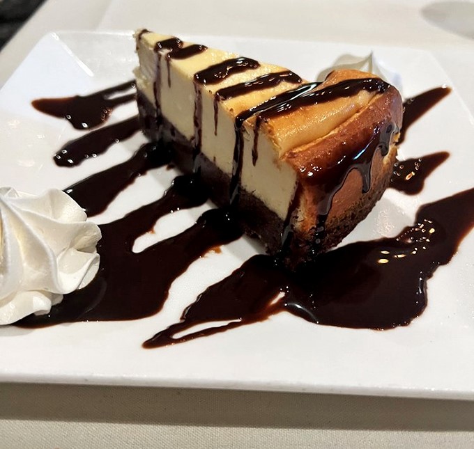Cheesecake drizzled with chocolate that makes you want to skip dinner entirely. The kind of dessert that silences conversation at the table.