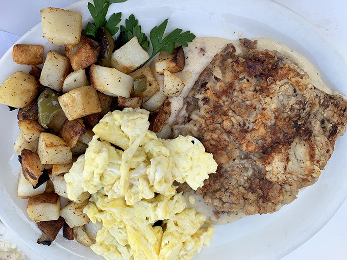 The holy trinity of breakfast comfort: golden-brown chicken fried steak, fluffy scrambled eggs, and home fries that look like they've been kissed by butter.